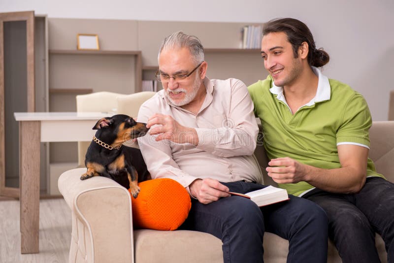 Two men with dog at home stock photo. Image of loyal - 217635144