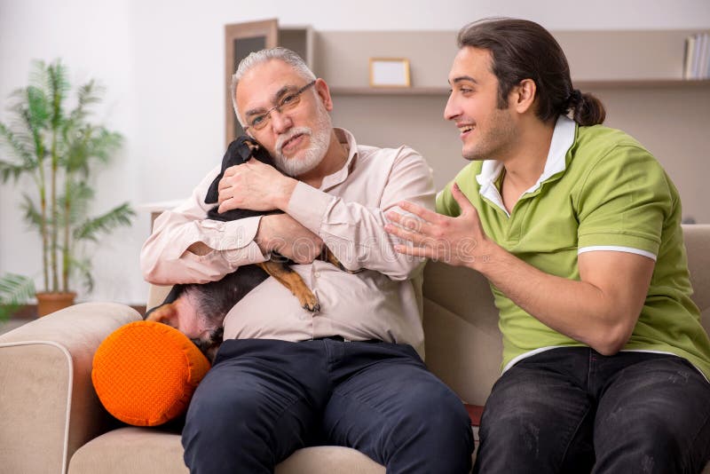 Two men with dog at home stock photo. Image of older - 221091862