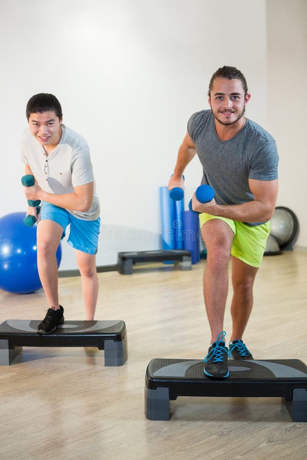 Two Men Doing Step Aerobic Exercise with Dumbbell on Stepper Stock ...