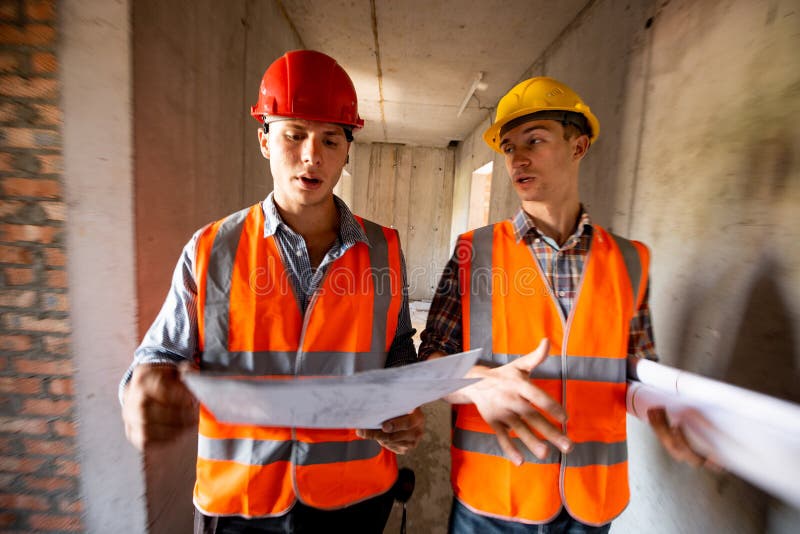 Two Men Dressed in Orange Work Vests and Helmets Work with Construction ...