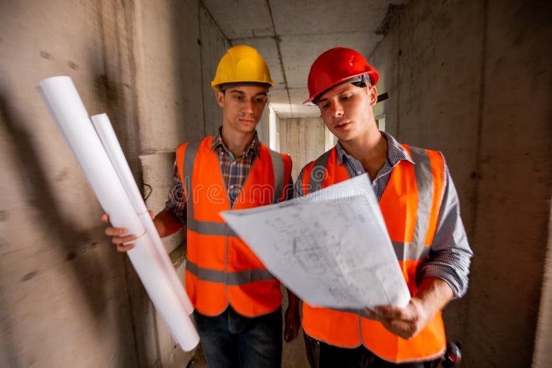 Two Men Dressed in Orange Work Vests and Helmets Work with Construction ...