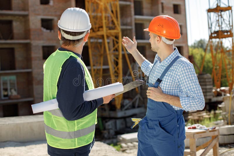 Two Men Engineers at a Construction Site are Looking at the Drawings ...