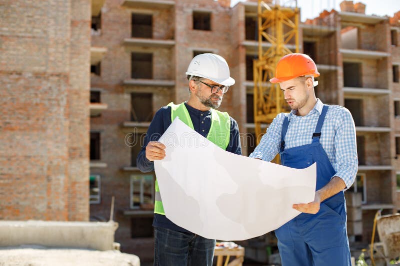 Two Men Engineers at a Construction Site are Looking at the Drawings ...