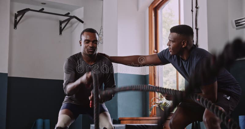 Two Men Showing Strength and Teamwork Using Ropes in Gym Workout ...