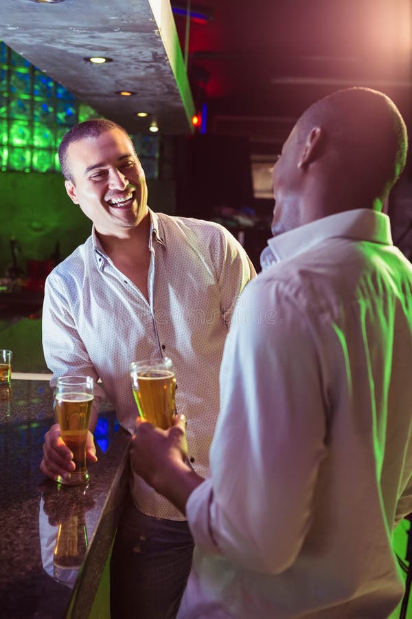 Two men having beer at bar stock image. Image of friendship - 67546593