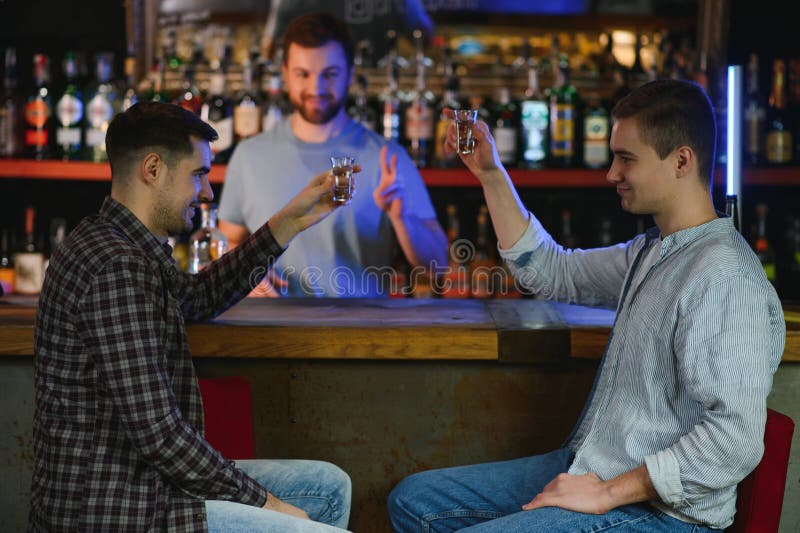Two Men is Having Fun Chatting with a Bartender in Bar Counter while ...