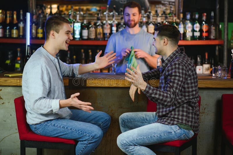 Two Men is Having Fun Chatting with a Bartender in Bar Counter while ...
