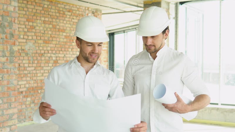 Two Men in Helmet Look at the Plan of the Building Stock Footage ...