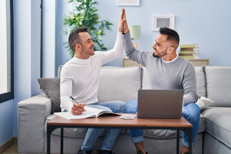 Two Men High Five with Hands Raised Up Sitting on Sofa at Home Stock ...