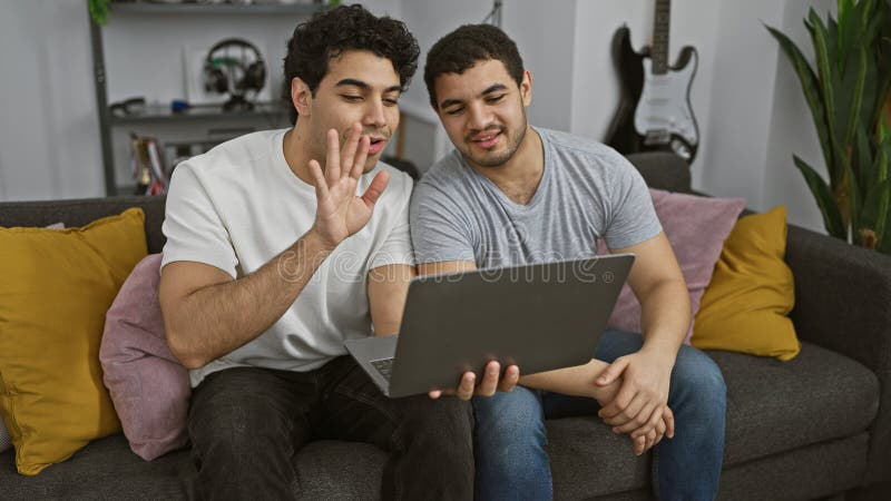Two Men Interacting with a Laptop on a Couch in a Home Environment ...