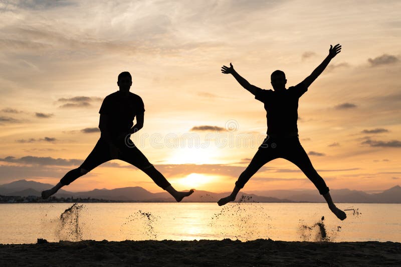 Two Men Jumping on the Beach at Sunset Stock Image - Image of sunset ...