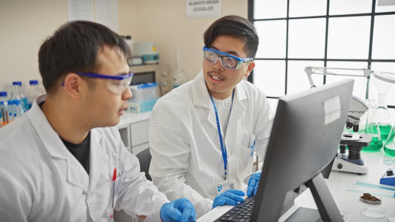 Two Men in Lab Coats Discussing Data on a Computer in a Modern ...