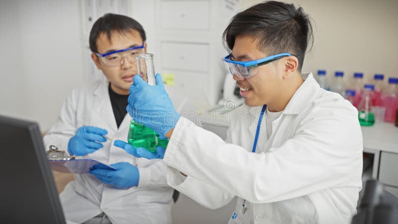 Two Men in Lab Coats Examining Chemical Flasks in a Laboratory Setting ...