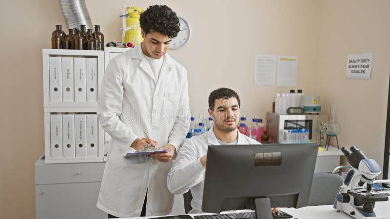 Two Men in Lab Coats Work in a Science Laboratory, One Using a Computer ...