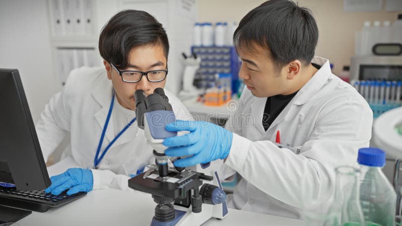 Two Men in Lab Coats Work Together in a Laboratory, One Using a ...