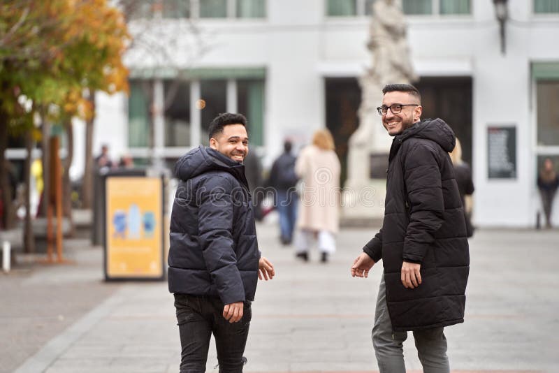Two Men Looking at the Camera and Smiling while Walking Down the Street ...