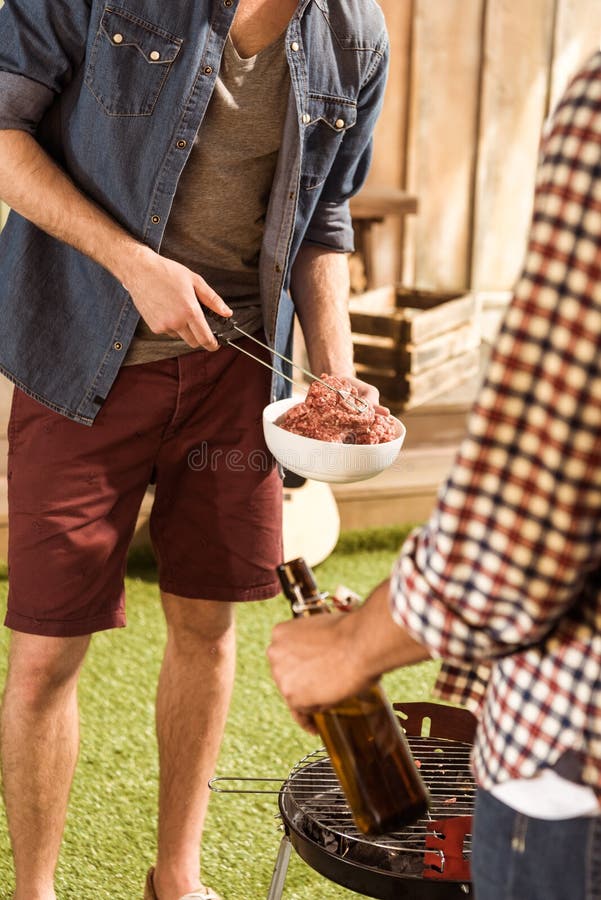 Two Men Preparing Raw Meat for Burgers and Drinking Beer Outdoors Stock ...