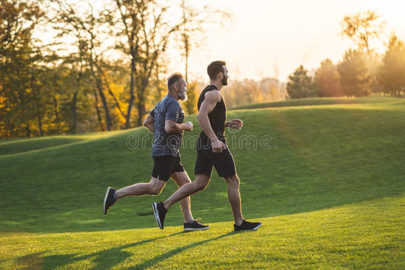 The Two Men Running on the Grass in the Park. Stock Image - Image of ...