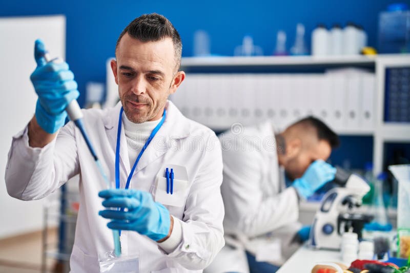 Two Men Scientists Pouring Liquid on Test Tube Using Microscope at ...