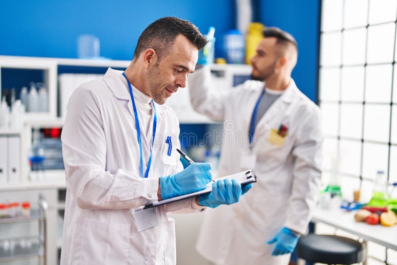 Two Men Scientists Writing on Document Holding Test Tube at Laboratory ...