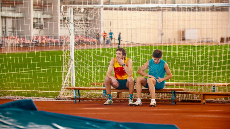 Two Men Sitting on the Bench while the Pole Vault Training Stock Image ...