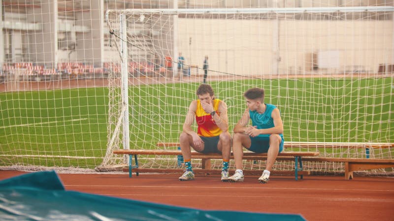Two Men Sitting on the Bench while the Pole Vault Training Stock ...