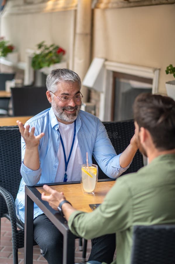 Two Men Sitting in the Cafe and Having an Interesting Conversation ...