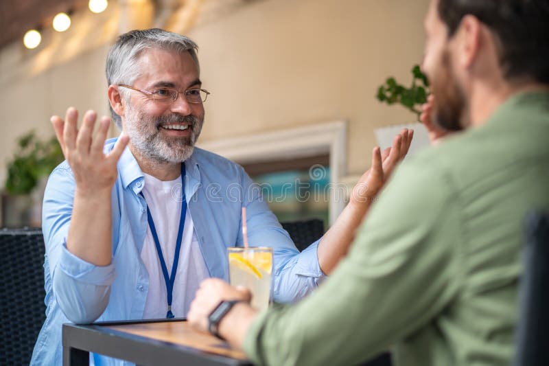 Two Men Sitting in the Cafe and Having an Interesting Conversation ...