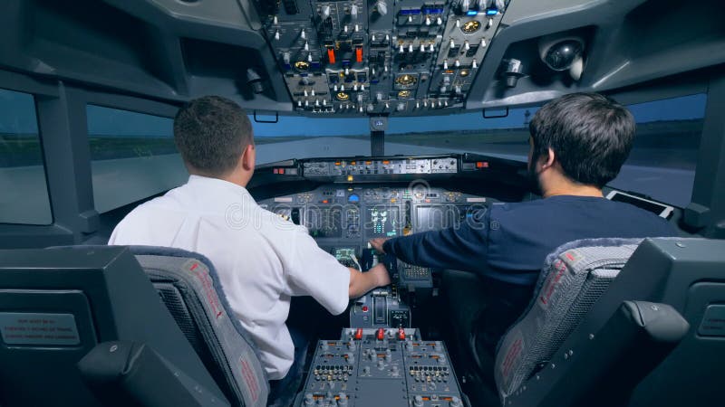 Two Men are Sitting in a Cockpit of a Flight Simulator. Cockpit Cabin ... Two Men are Sitting in a Cockpit of a Flight Simulator. Cockpit Cabin ...