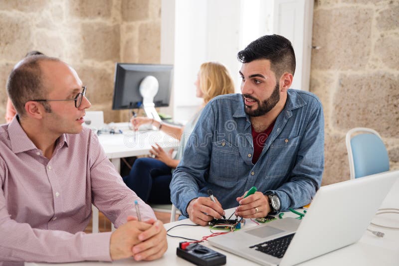 Two Men Sitting at a Desk Talking Over a Computer Stock Image - Image ...