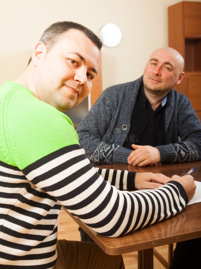 Two men sitting at table stock photo. Image of working - 43762848