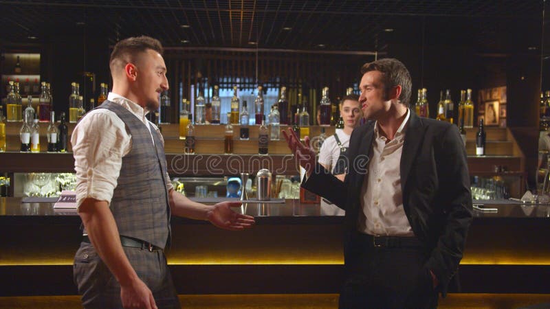 Two Men Stand at the Bar and Talk with Each Other Agressively Stock ...