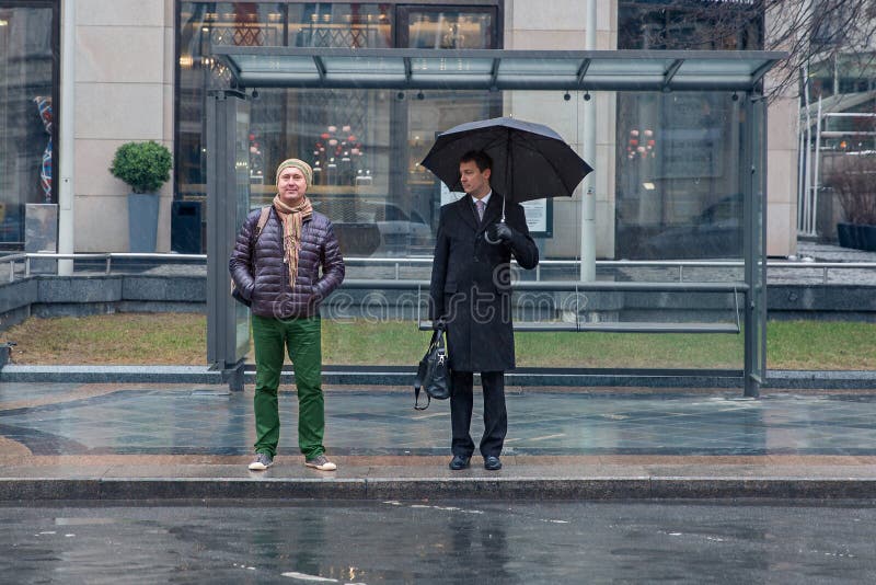 Two Men Stand at the Bus Stop, One of Them is Sad, Another is Ch Stock ...