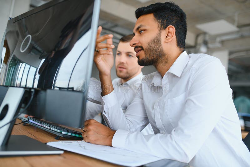Two Men Traders Sitting at Desk at Office Together Looking at Data ...