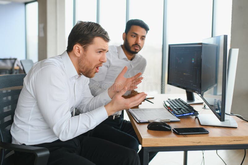 Two Men Traders Sitting at Desk at Office Together Looking at Data ...