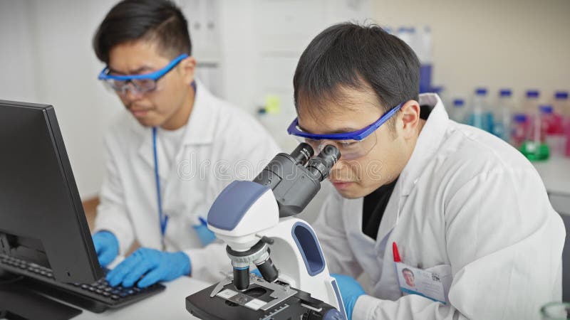 Two Men Using a Microscope and a Laptop in a Laboratory Setting ...