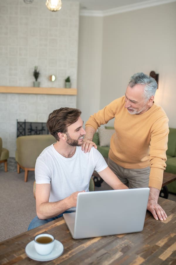 Two Men Watching Something on a Laptop and Looking Involved Stock Photo ...