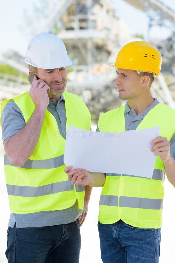 Two Men Wearing Reflective Clothing Looking at Plans on Site Stock ...