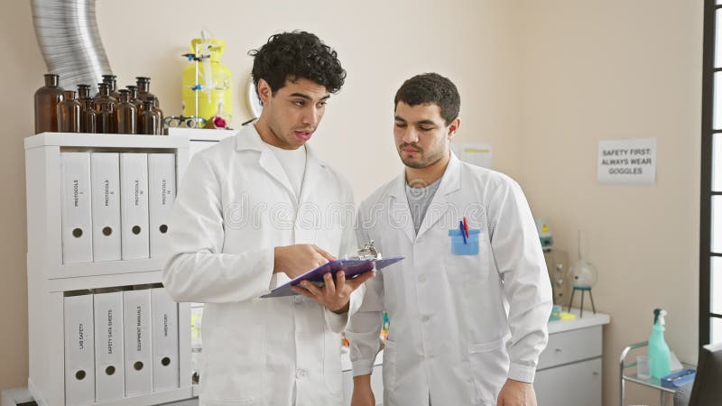 Two Men Working As Scientists in a Laboratory, Discussing a Clipboard ...