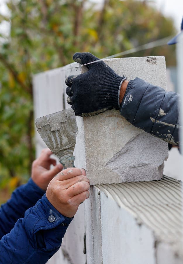 Two Men are Working on a Brick Wall, One of Them Holding a Trowel Stock ...