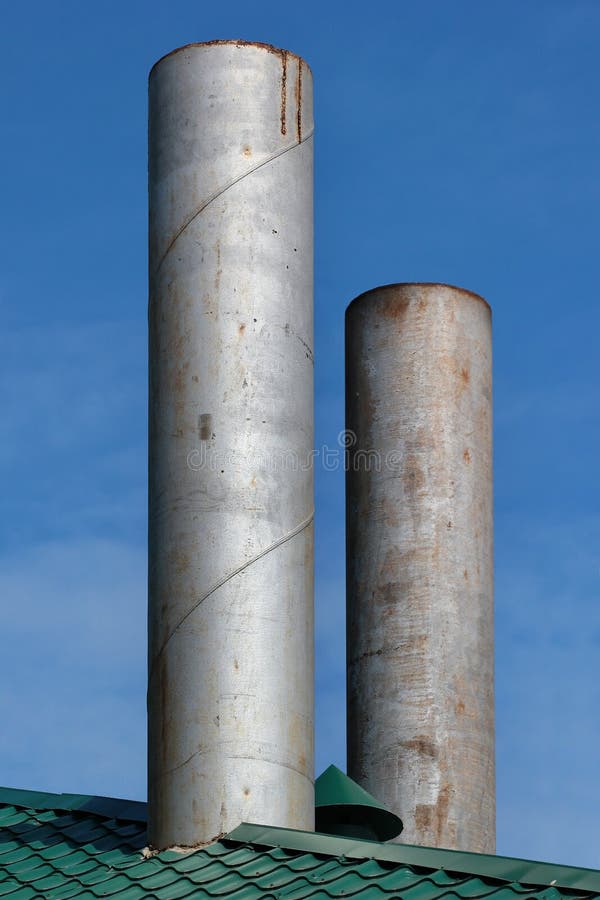 Two Metal Chimneys on the Roofs of Factory. Against Blue Sky Stock ...