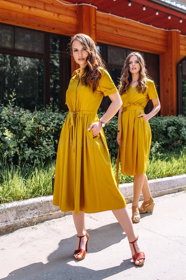Two Models on the Street in Mustard Colored Dresses Stock Image - Image ...