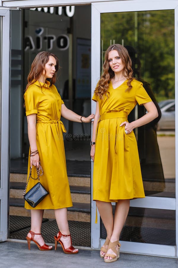 Two Models on the Street in Mustard Colored Dresses Stock Photo - Image ...