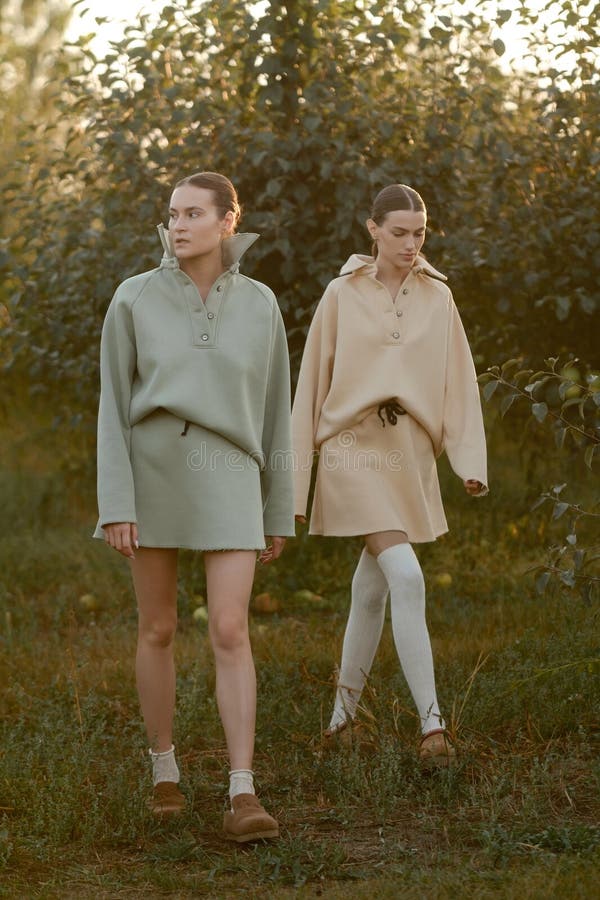Two Models in Stylish Tracksuits Pose in Apple Orchard at Sunset . the ...