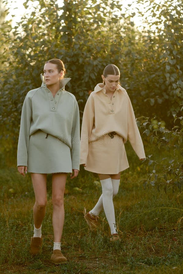Two Models in Stylish Tracksuits Pose in Apple Orchard at Sunset . the ...
