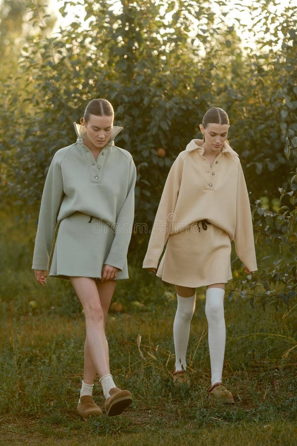Two Models in Stylish Tracksuits Pose in Apple Orchard at Sunset . the ...