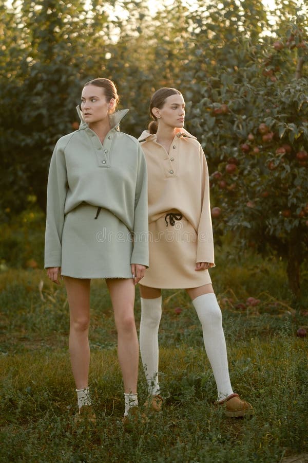 Two Models in Stylish Tracksuits Pose in Apple Orchard at Sunset . the ...