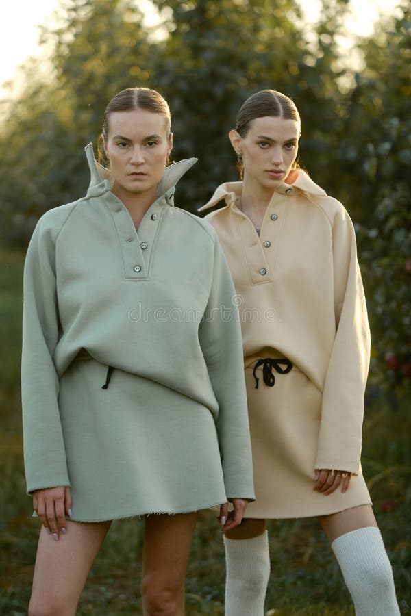 Two Models in Stylish Tracksuits Pose in Apple Orchard at Sunset . the ...