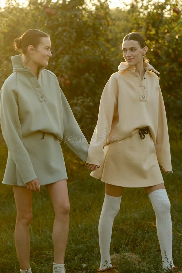 Two Models in Stylish Tracksuits Pose in Apple Orchard at Sunset . the ...