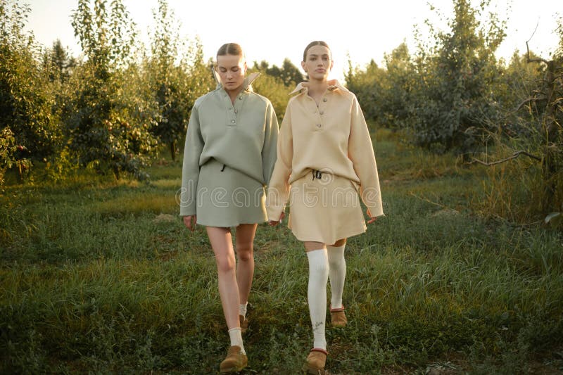 Two Models in Stylish Tracksuits Pose in Apple Orchard at Sunset . the ...